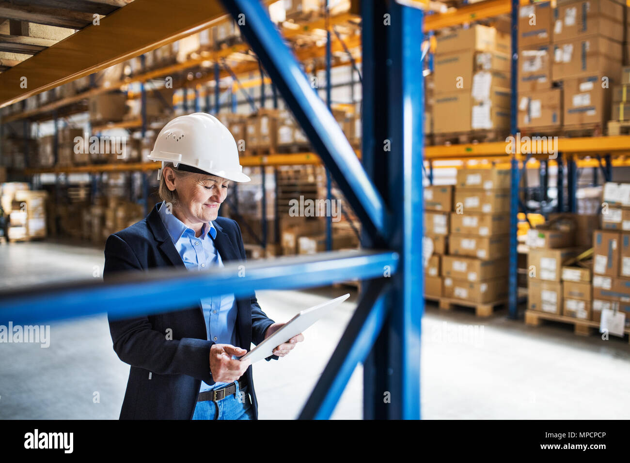 Senior woman warehouse manager or supervisor with tablet, working Stock ...