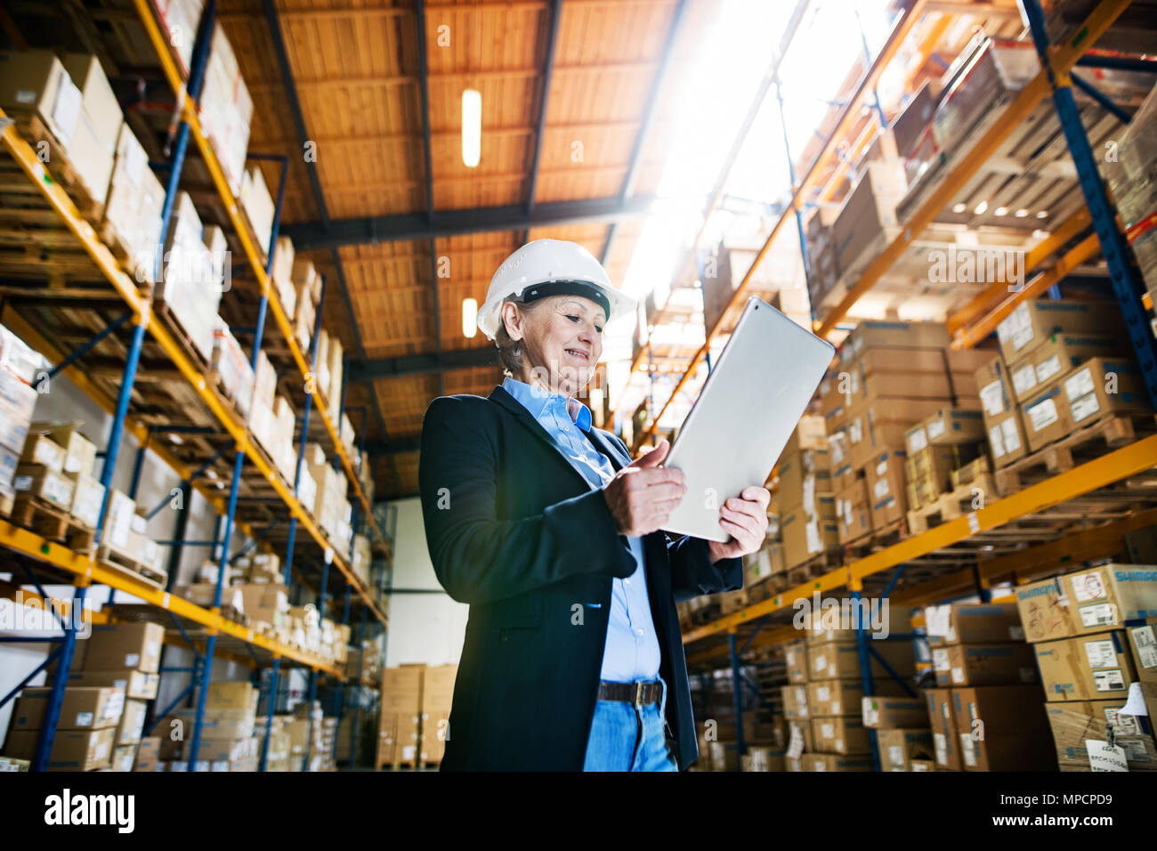 Senior woman warehouse manager or supervisor with tablet, working Stock ...