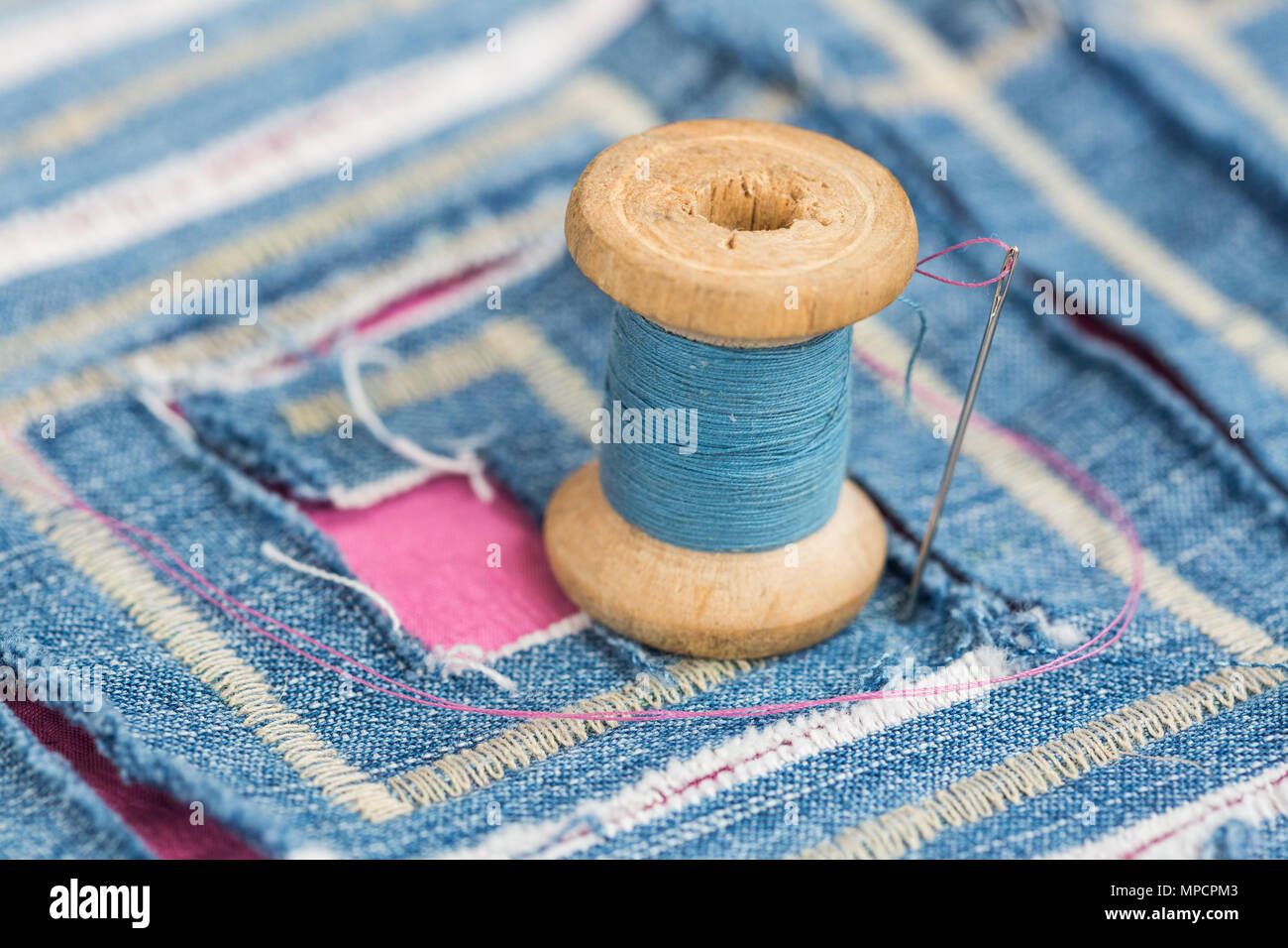 sewing and embroidery concept - installation of a needle and spool of ...