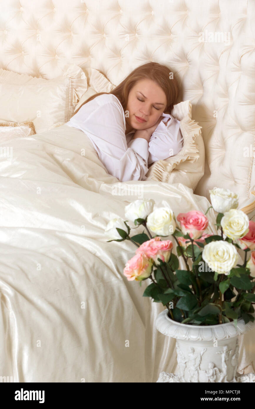 Romance. Beautiful sleeping woman in white bed with red roses Stock ...
