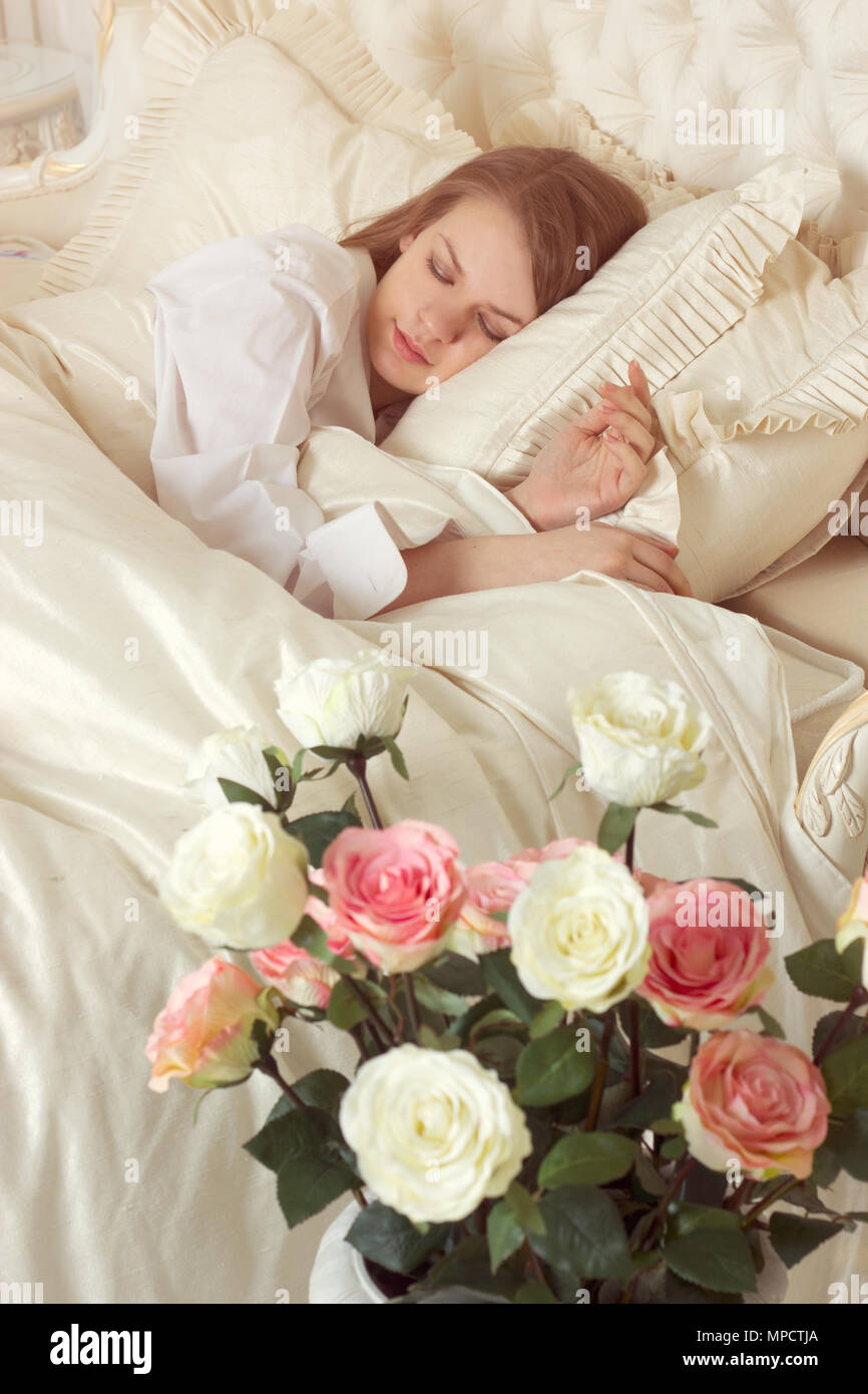 Romance. Beautiful sleeping woman in white bed with red roses Stock ...