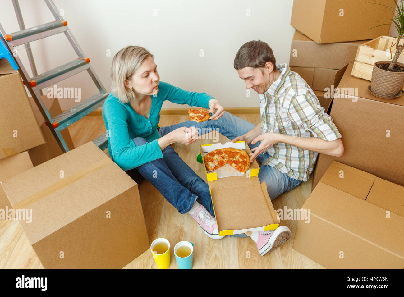 Photos of women and men eating pizza among cardboard boxes Stock Photo ...