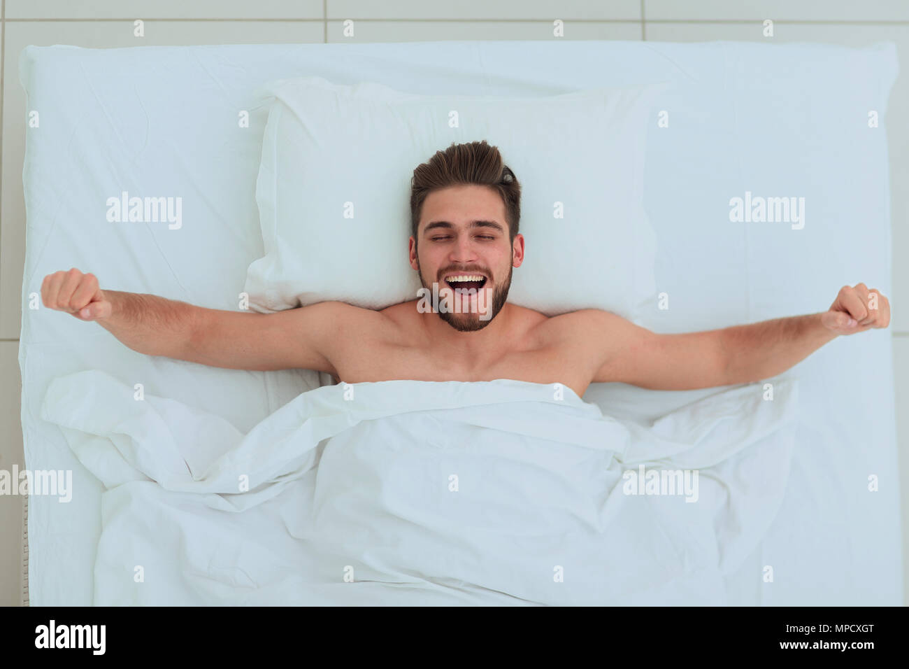 top view. happy man waking up in a comfortable bed Stock Photo - Alamy