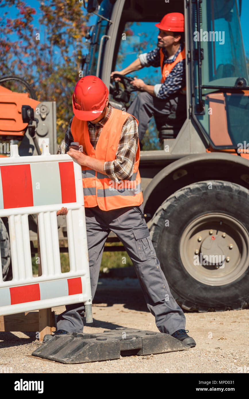 Worker setting up earthworks construction site Stock Photo - Alamy
