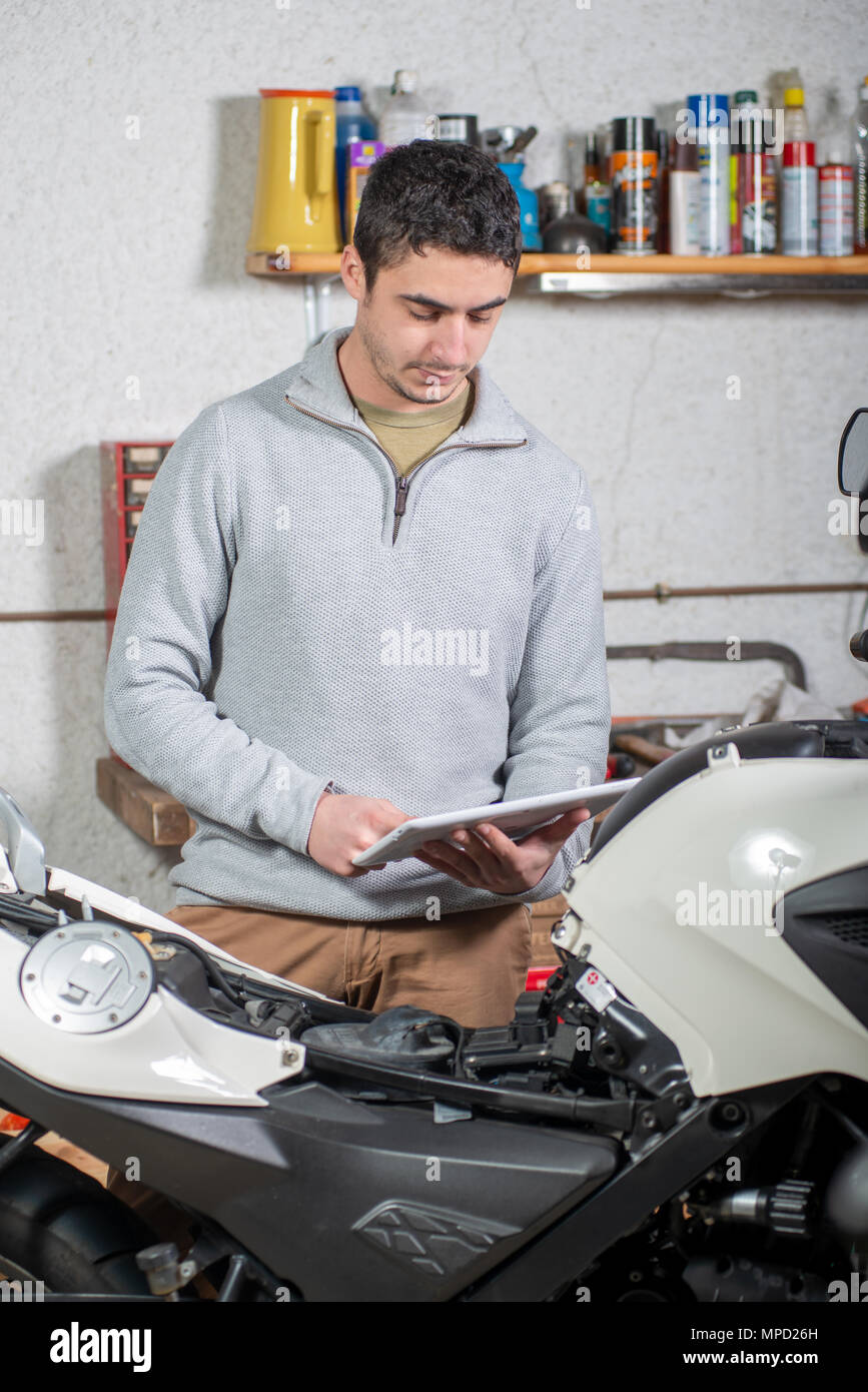 Man using tablet next to motorcycle workshop hi-res stock photography ...