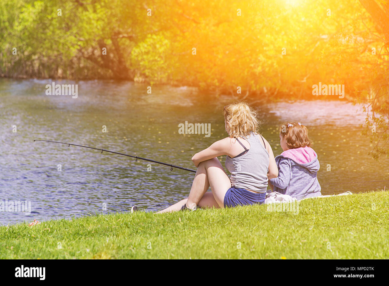 mother and daughter fishing in the lake, in the pond, sitting on the ...