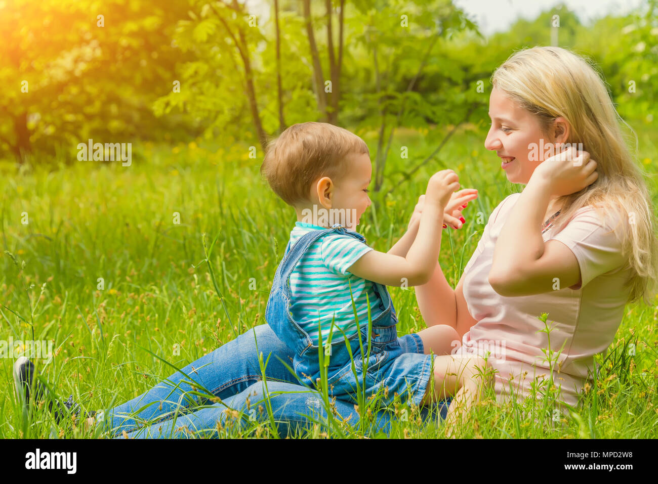 mother and child in nature in the Park, resting on the green grass in ...