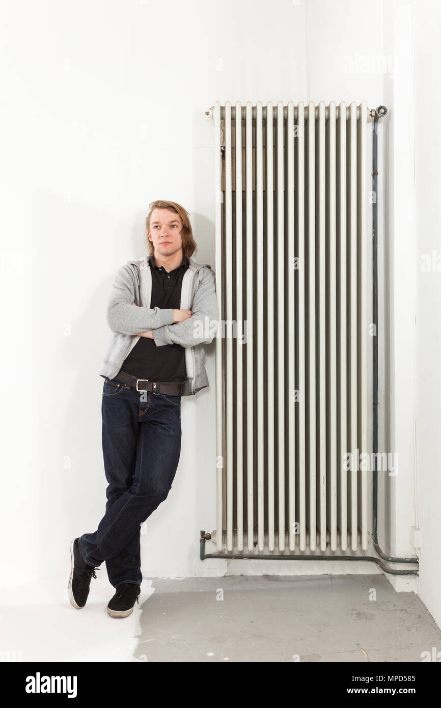 Portrait of young man. Man leaning on the radiator Stock Photo - Alamy