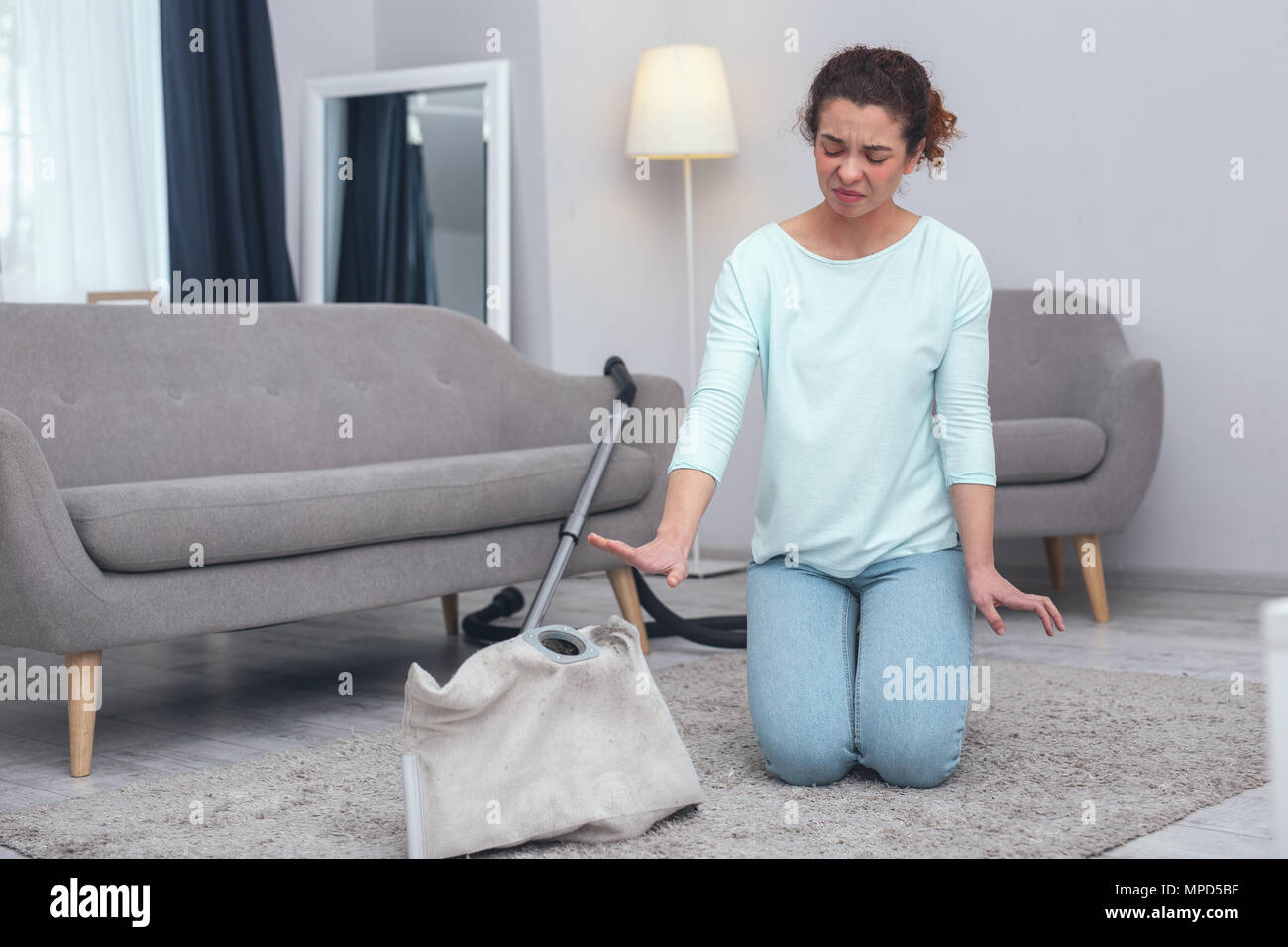 Young woman with a vacuum cleaner feeling disgusted by dust Stock Photo ...