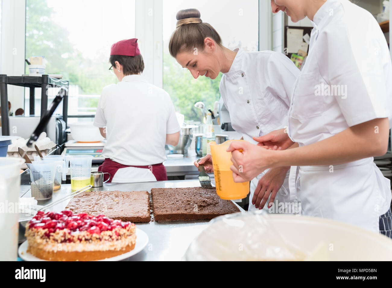 Three pastry bakers in confectionary preparing fruit pies Stock Photo ...