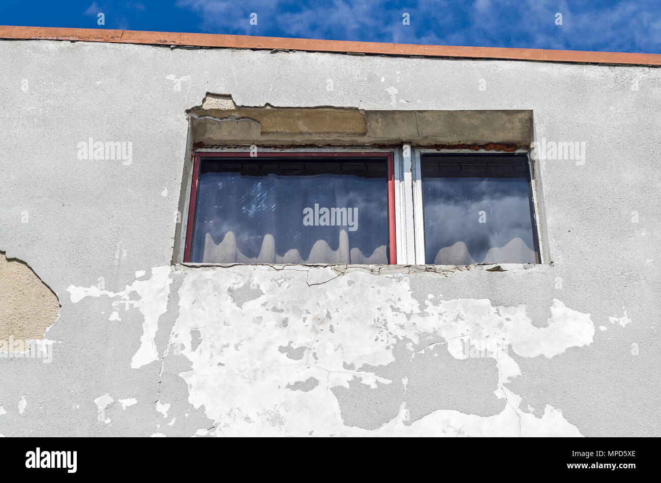 Damaged abandoned house facade with one dirty window with a draperies ...