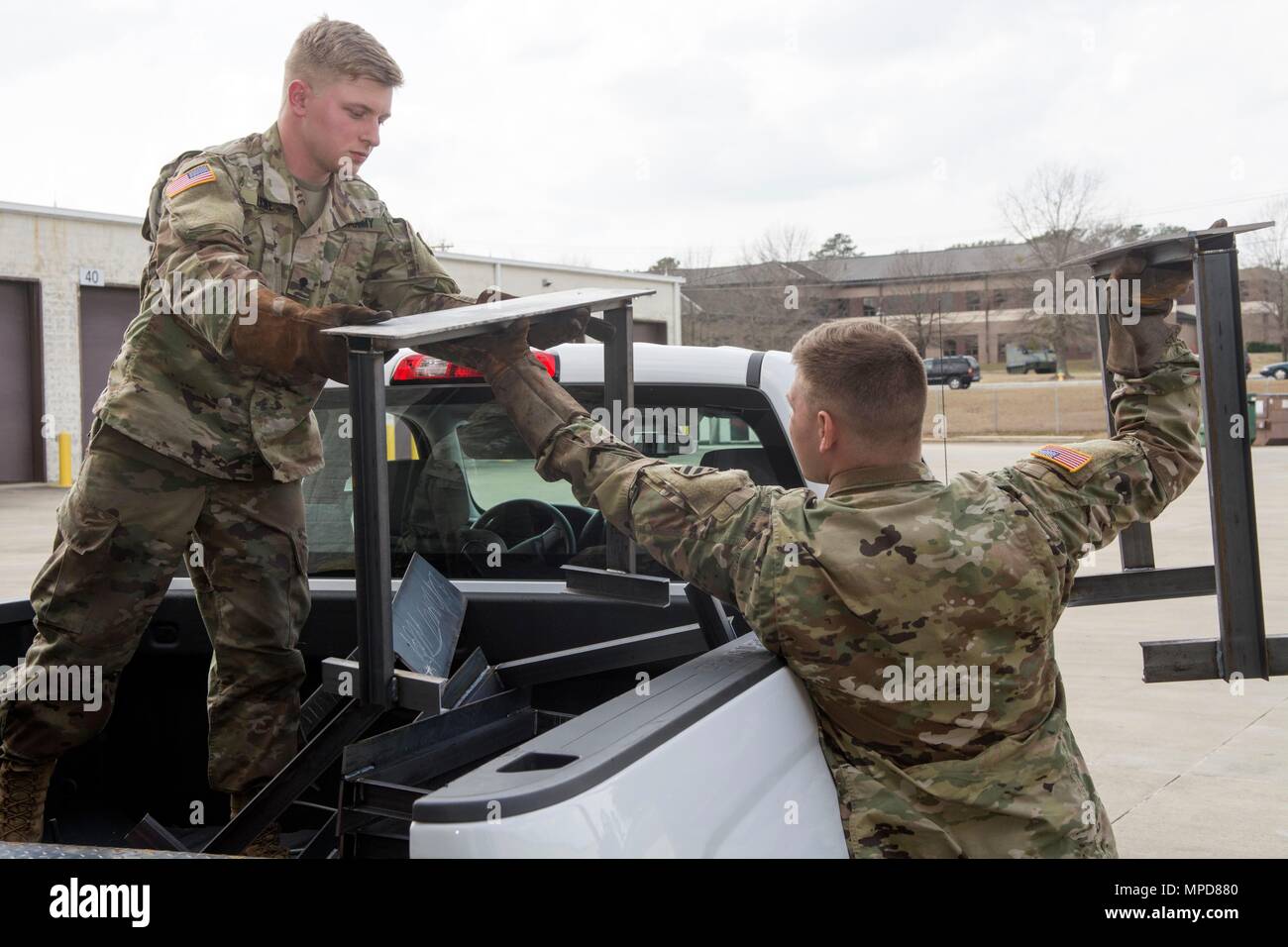Spc. Brett Alkire hands Spc. Nicholas Scott, both machinist/welders ...