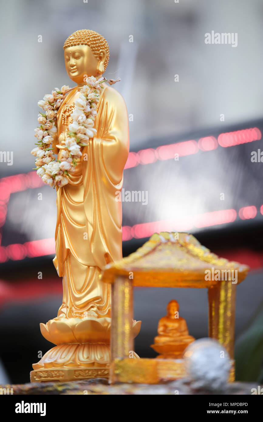 Golden color buddha statue decorated with flower garland mounted on a ...