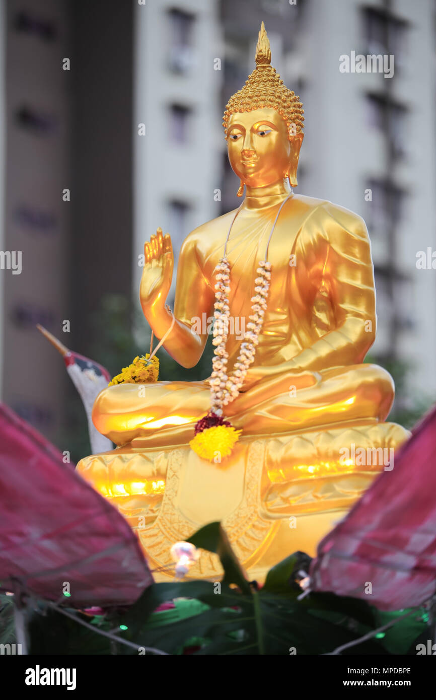 Golden color buddha statue decorated with flower garland mounted on a ...