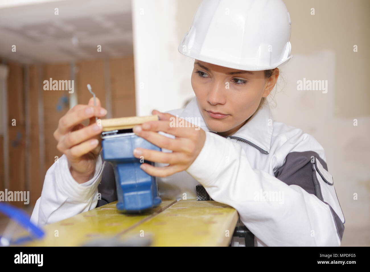 female construction worker fixing sanding machine Stock Photo - Alamy