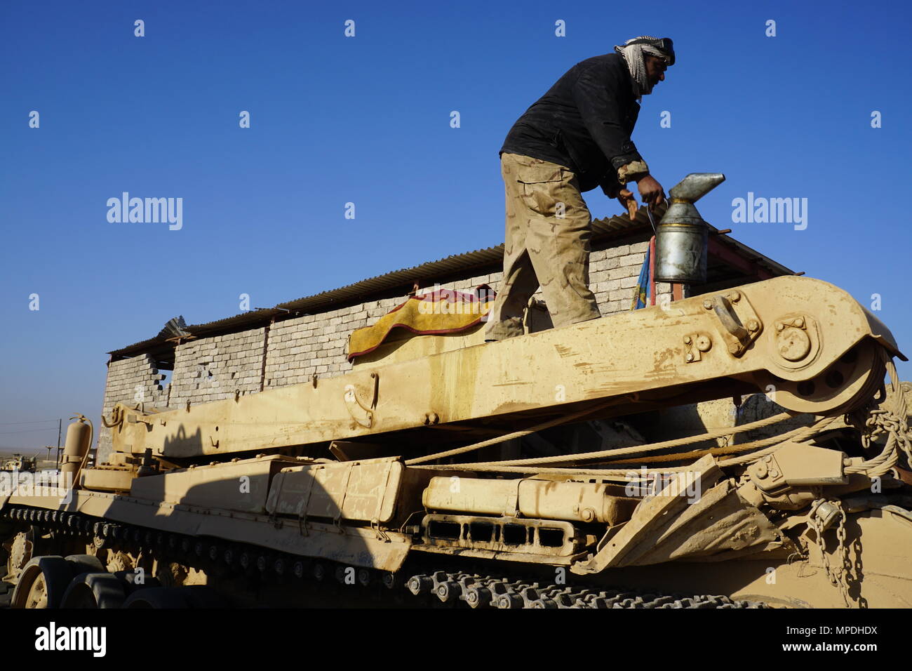 An Iraqi soldier with the 9th Iraqi Army Division stands with a can of ...