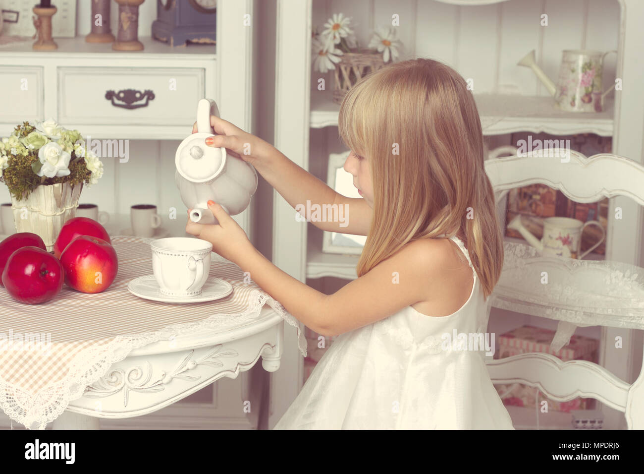 Little girl sitting at the table with fruits and teapot Stock Photo - Alamy