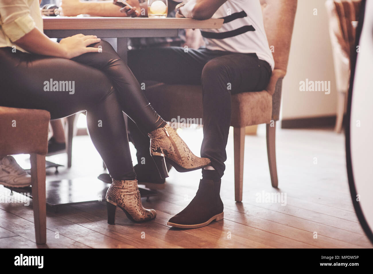Girl flirting with a guy touching leg her foot under the table in a ...