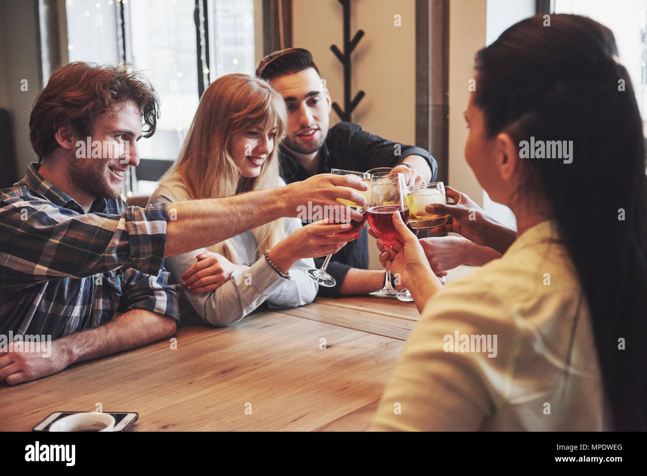 Group of young friends having fun and laughing while dining at table in ...