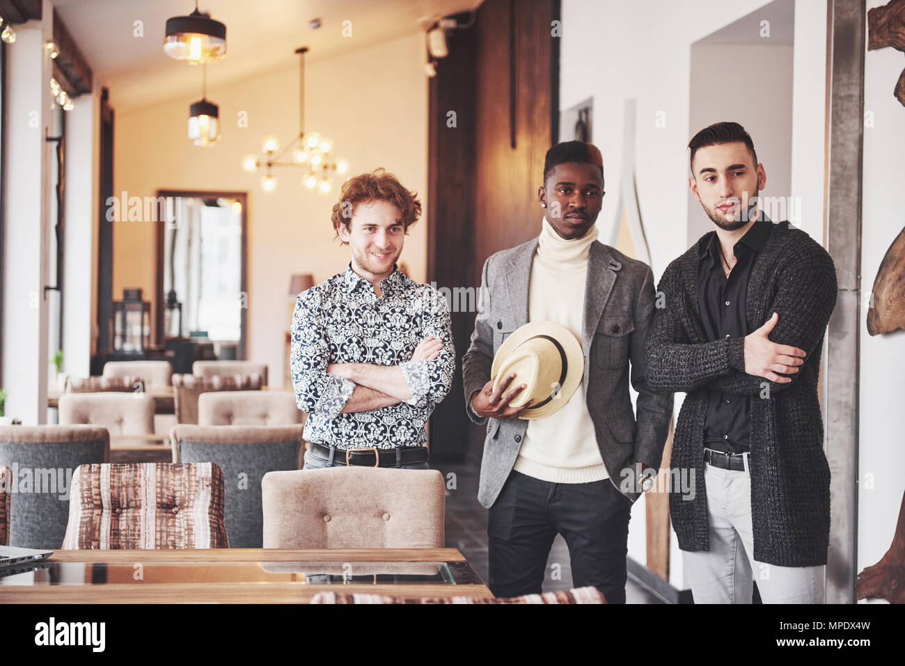 Three cheerful young men standing and smiling together Stock Photo - Alamy