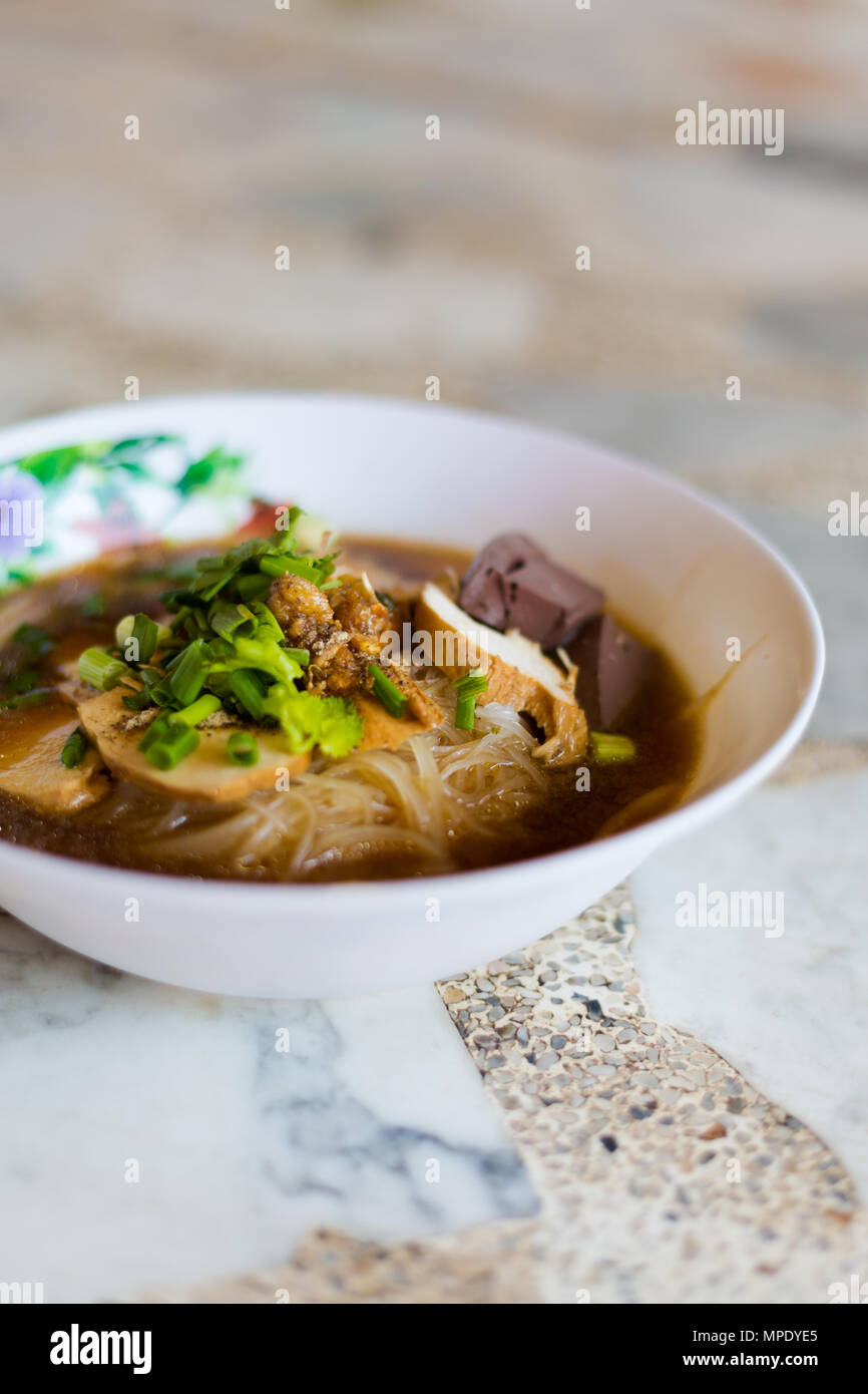 Fresh made thai dark broth noodle soup served with tofu slices, spring ...