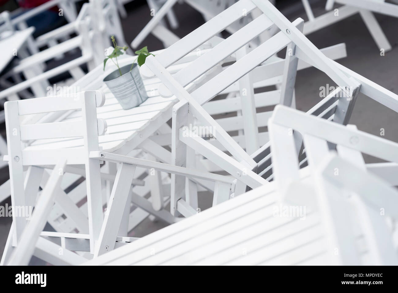 Heaps of inverted white plastic chairs on tables in closed restaurant ...