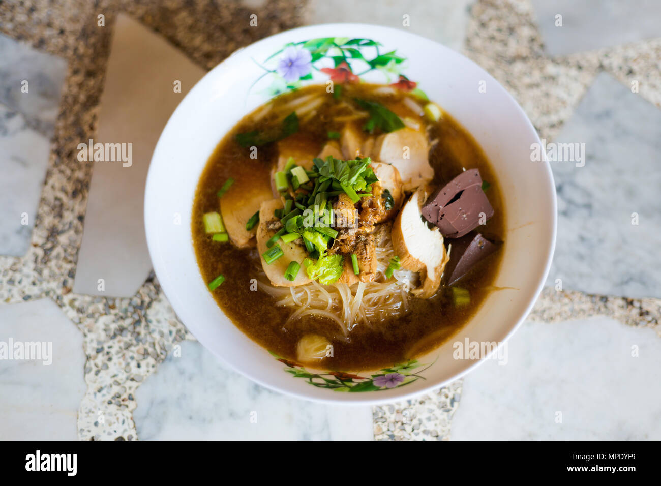 Fresh made thai dark broth noodle soup served with tofu slices, spring ...