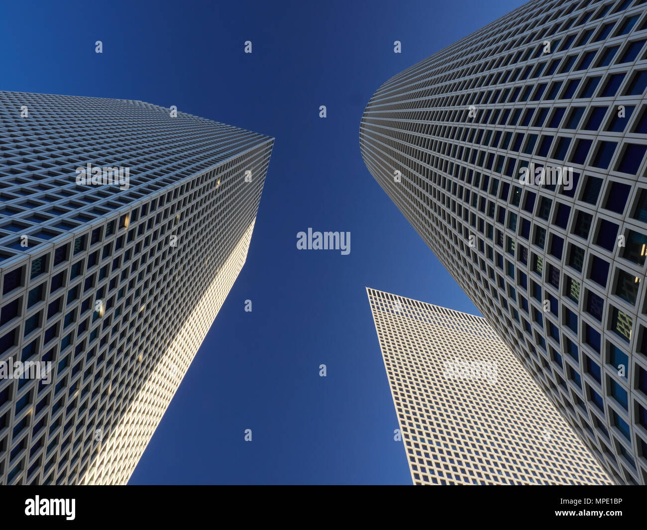 High walls of three white skyscrapers with squares of windows on blue ...