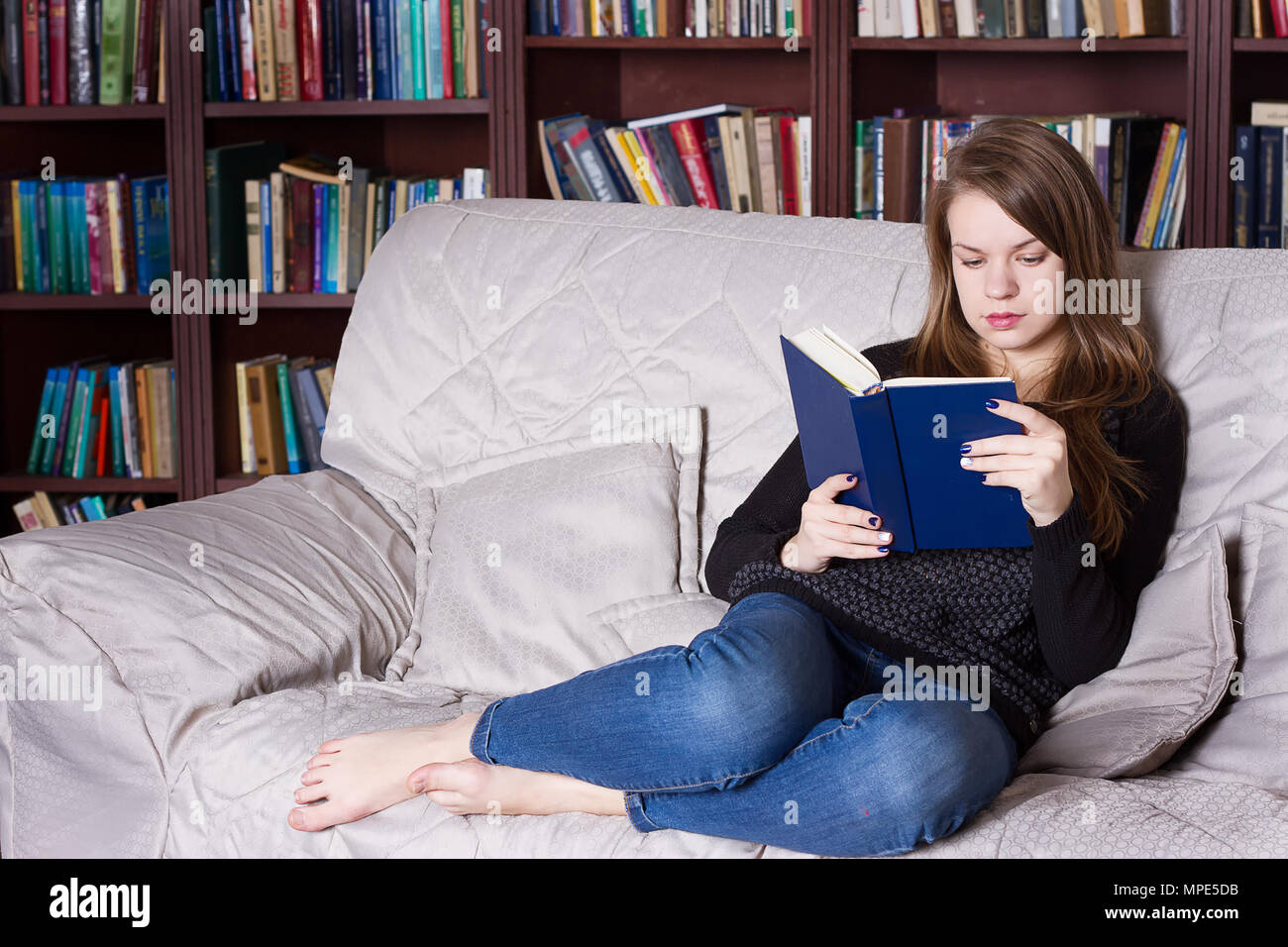 Woman at the library reading a book Stock Photo - Alamy