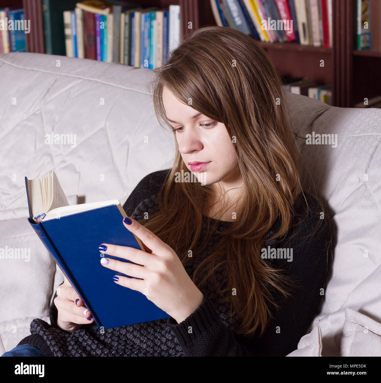 Woman at the library reading a book Stock Photo - Alamy