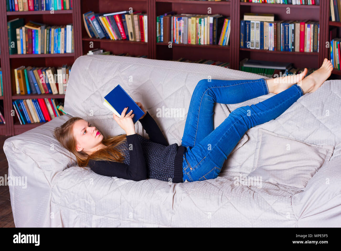 beautiful girl reading a book on sofa Stock Photo - Alamy