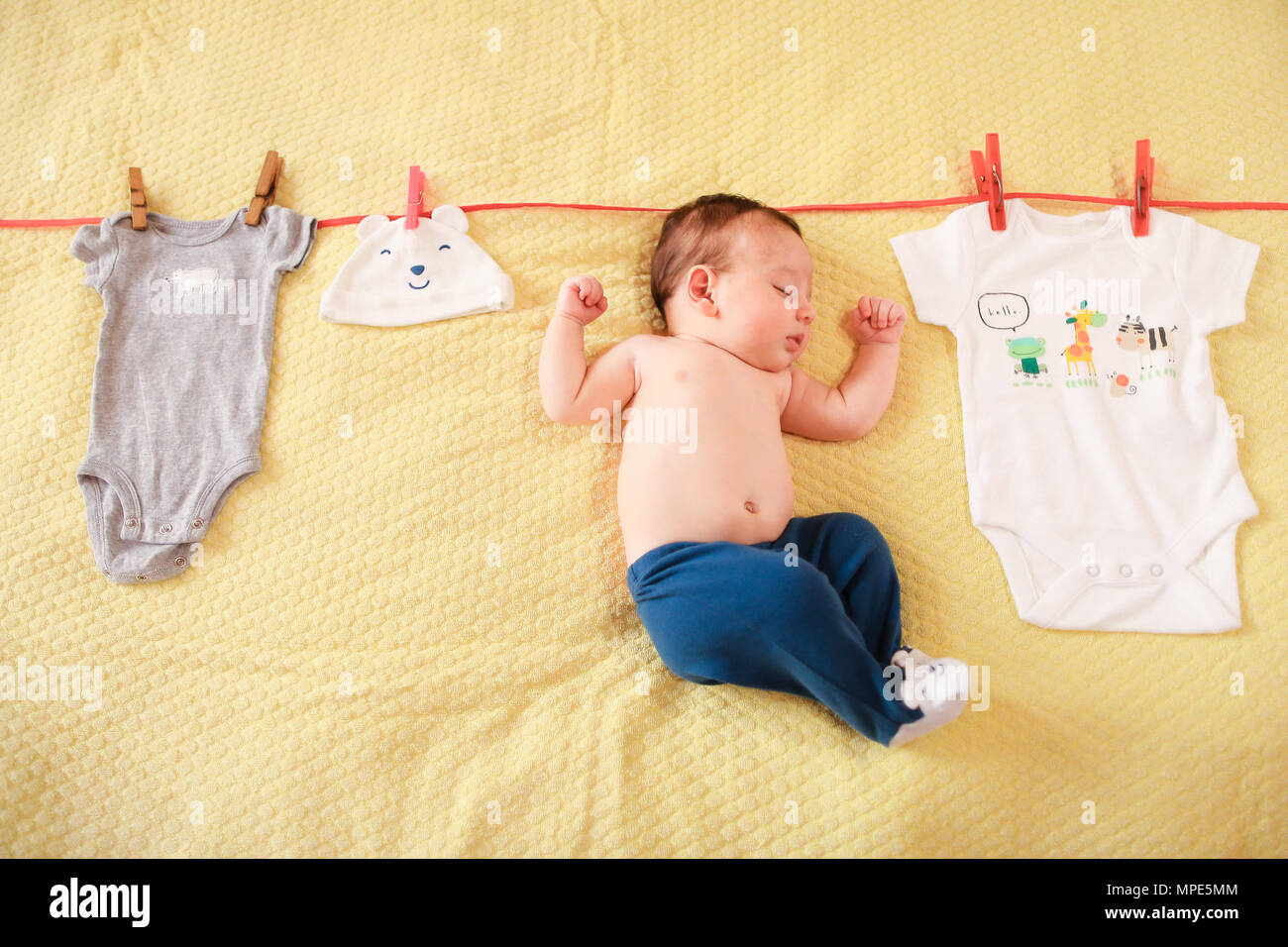 Little nice baby hanging with clothes on rope Stock Photo - Alamy