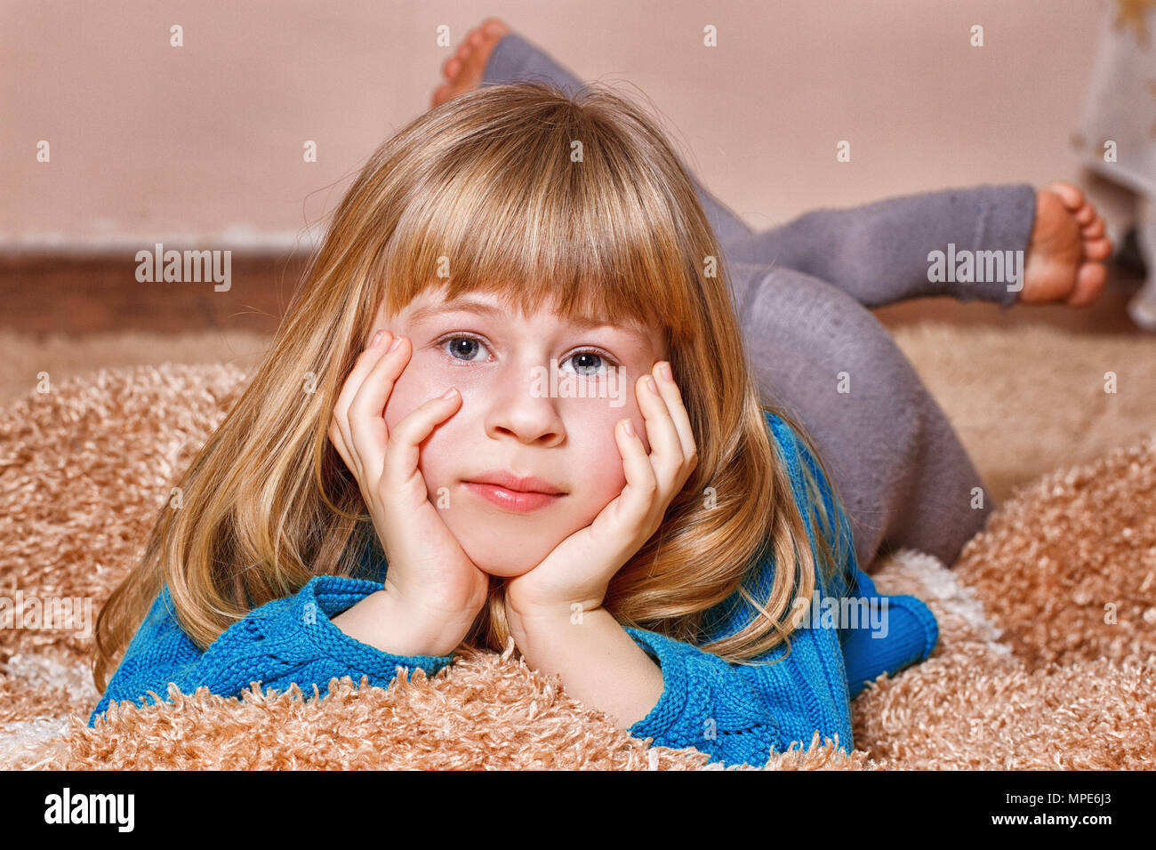 little girl with funny tails is lying on the white carpe Stock Photo ...
