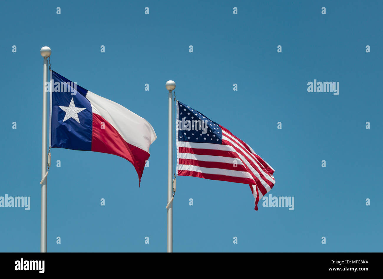 The state flag of Texas and American flag waving in the wind on ...