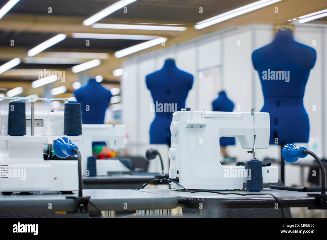 Interior of garment factory . Closes making atelier with several sewing machines. Tailoring ...