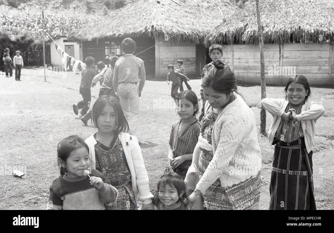 A WOMEN WITH SOME CHILDREN AROUND HER AND OTHER KIDS ARE PLAYING IN THE ...