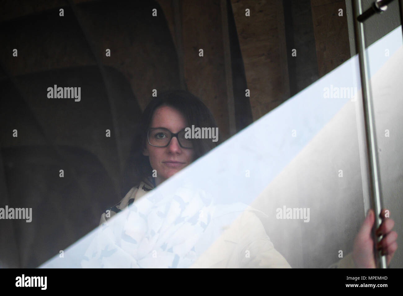 Dark haired woman wearing glasses opening a glass door. Medium shot ...