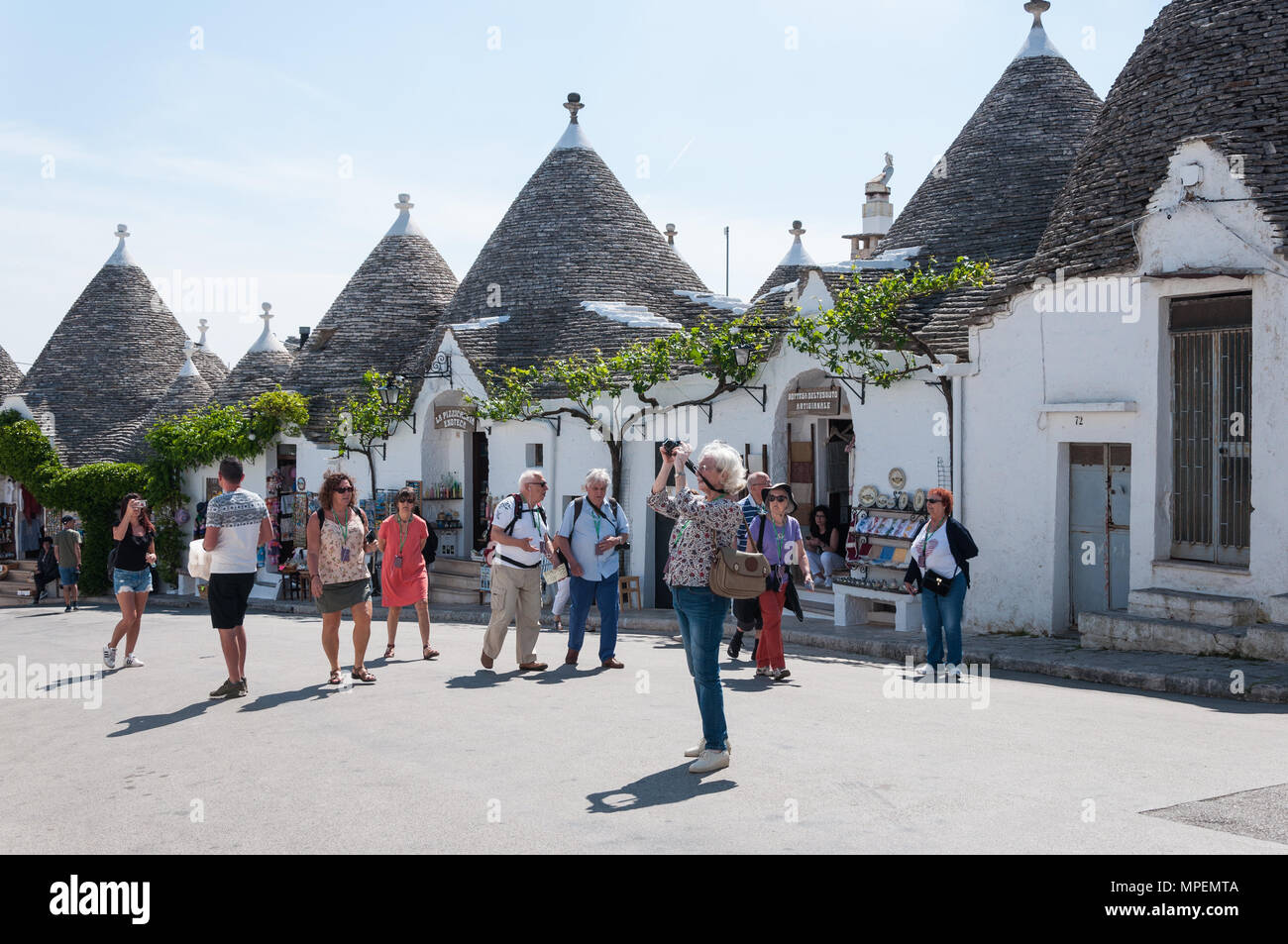 Tourists wander along the streets lined with trulli, traditional stone ...