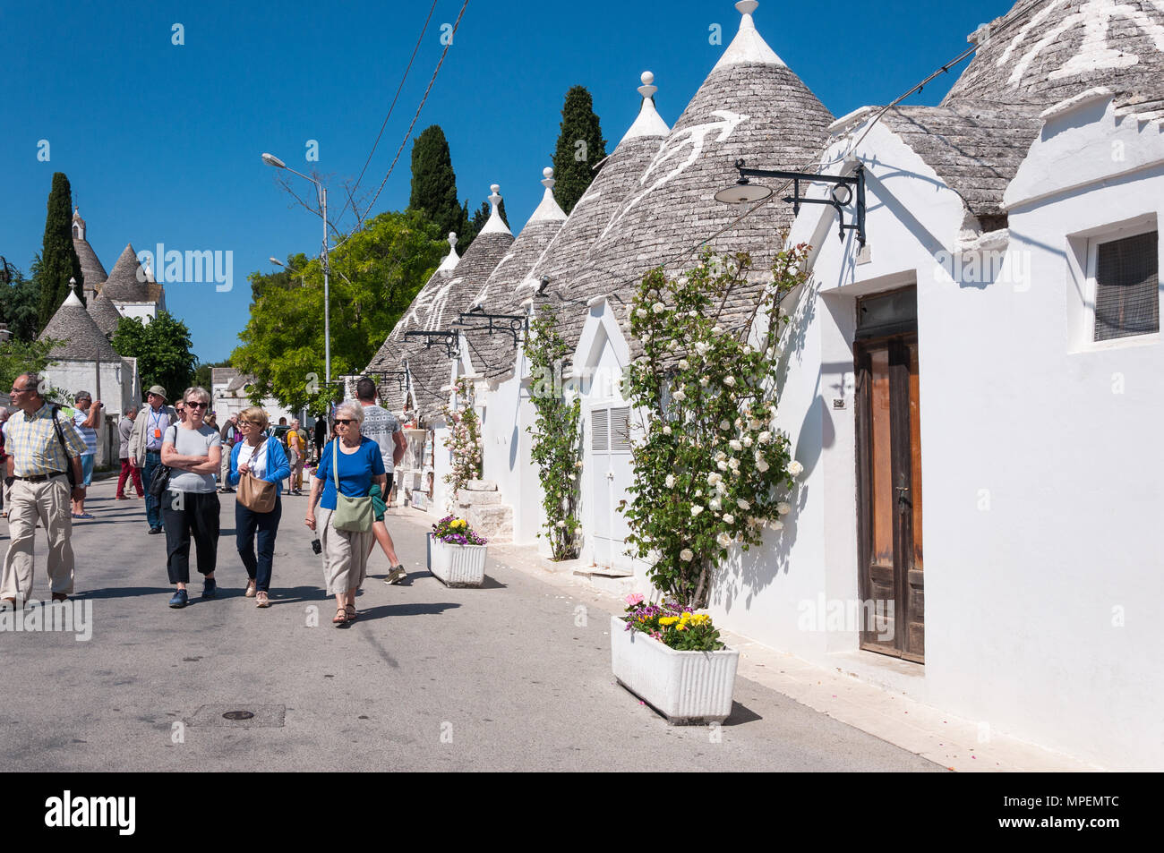 Tourists wander along the streets lined with trulli, traditional stone ...
