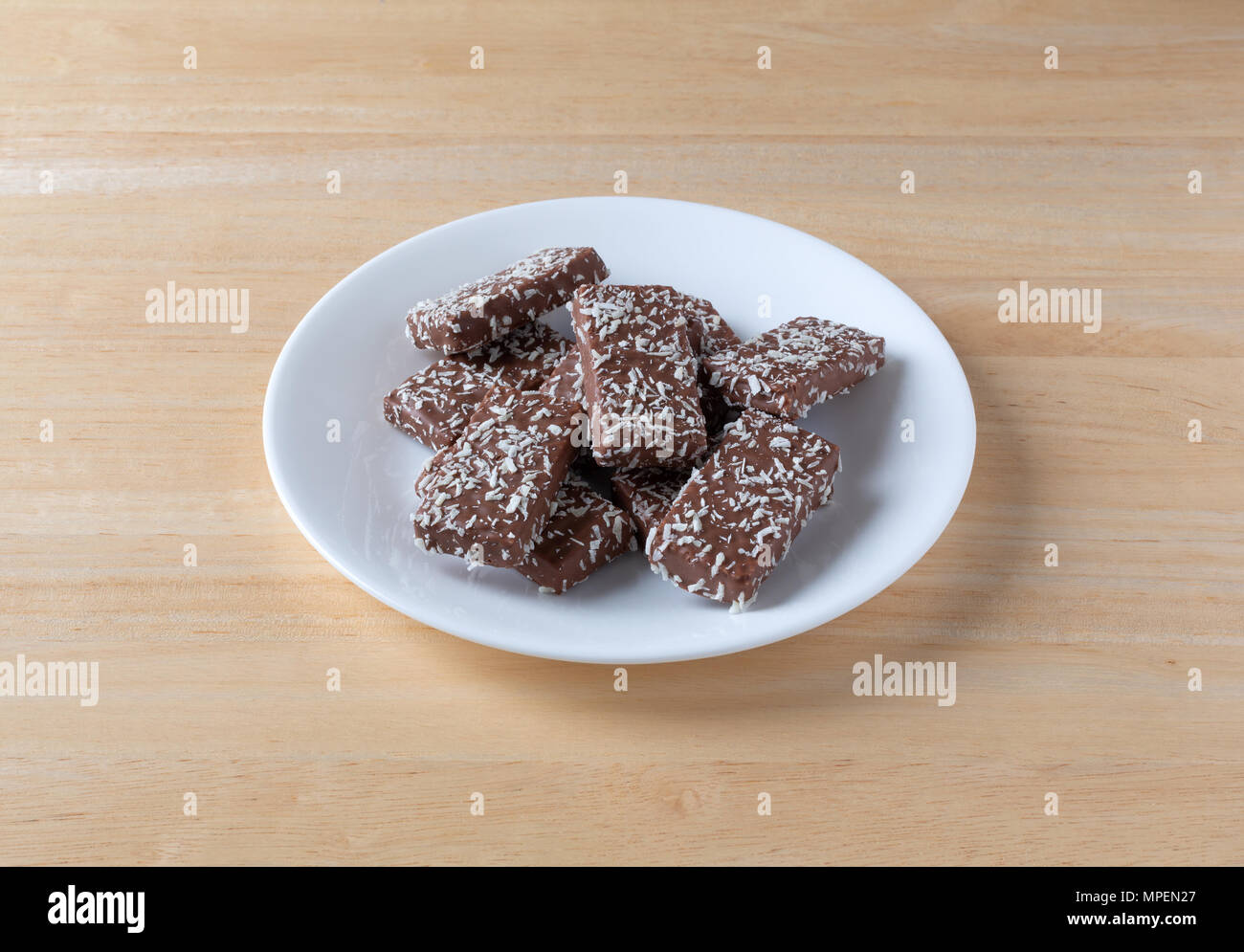 Several chocolate wafer cookies with coconut flakes on a white plate ...