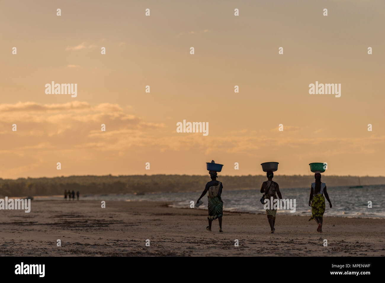 African woman walk on the beach with parcels on their heads in ...