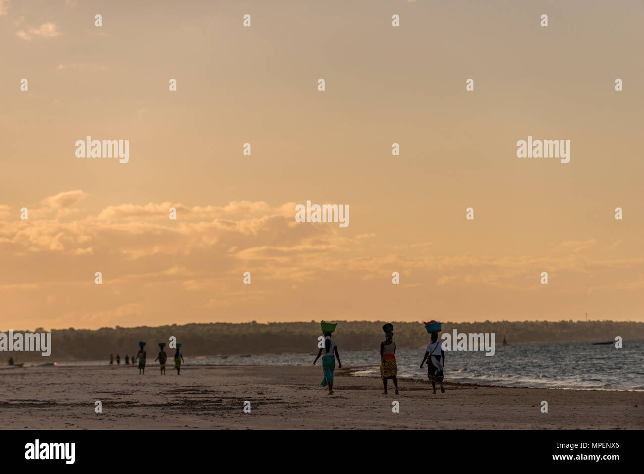 African woman walk on the beach with parcels on their heads in ...