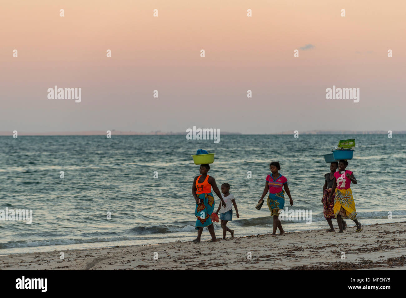 African woman walk on the beach with parcels on their heads in ...