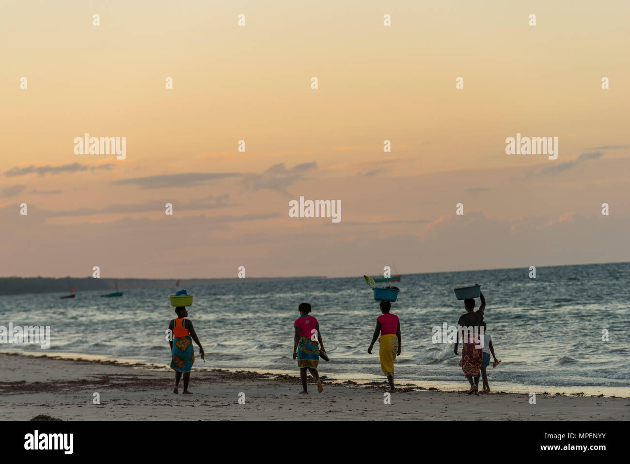 African woman walk on the beach with parcels on their heads in ...