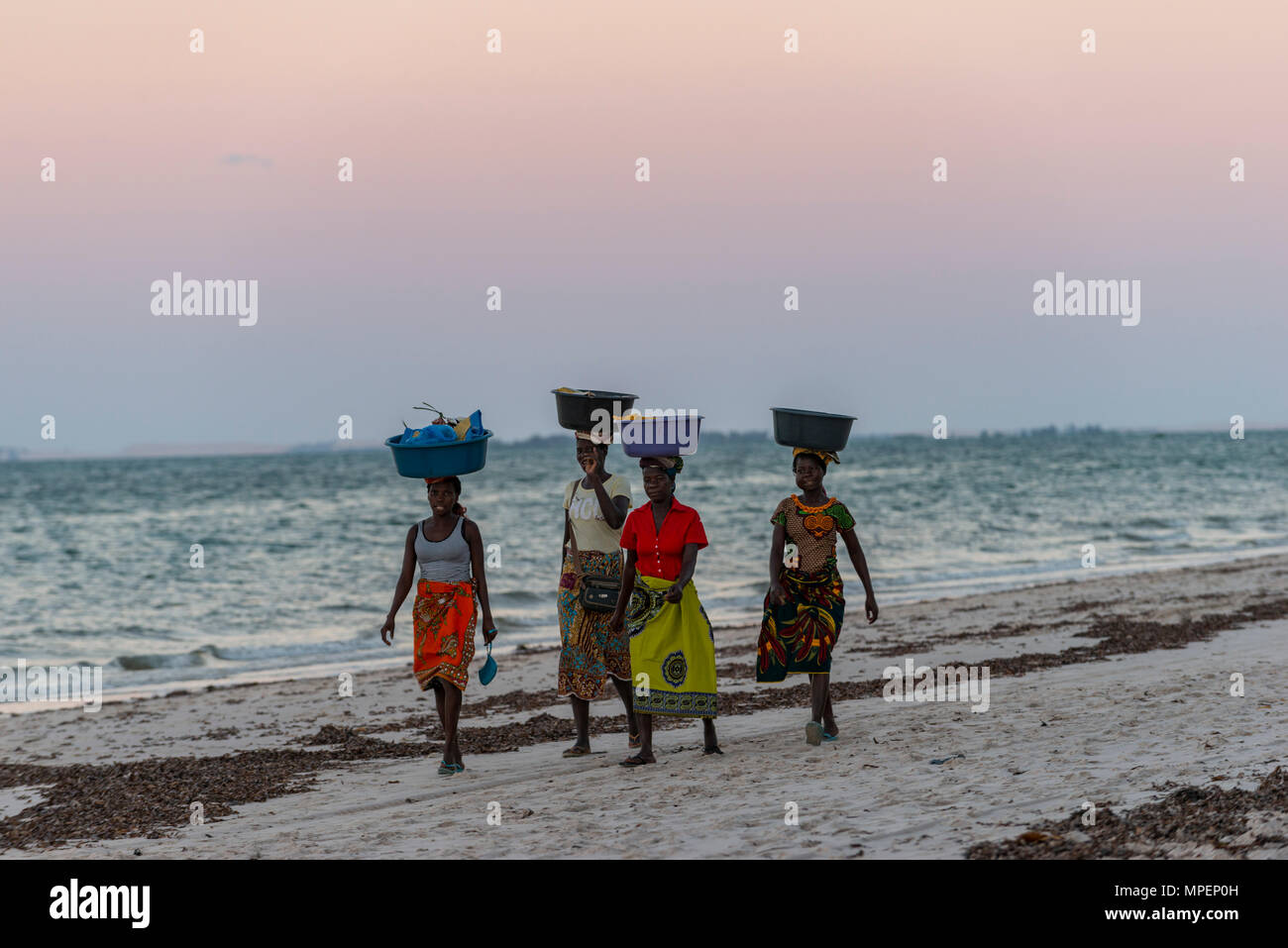 African woman walk on the beach with parcels on their heads in ...