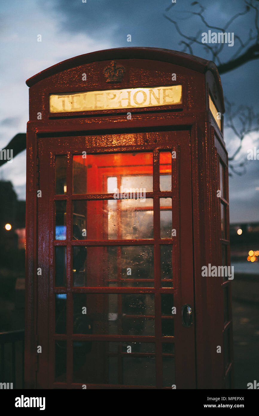 Toned vertical image of a red English phone booth in the evening, with ...