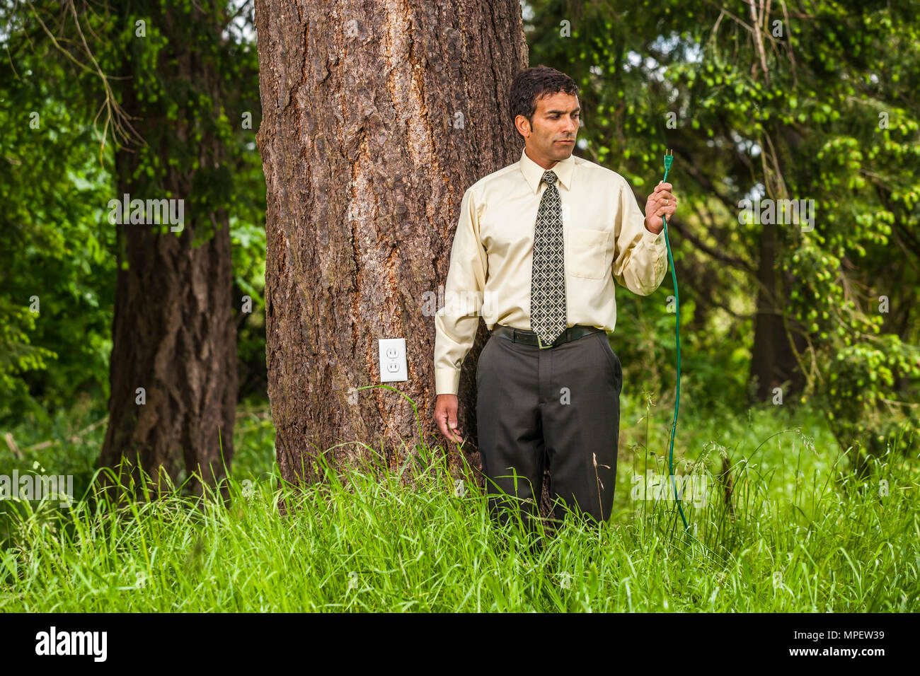 Conceptual shot of a businessman holding a green extension cord with an ...