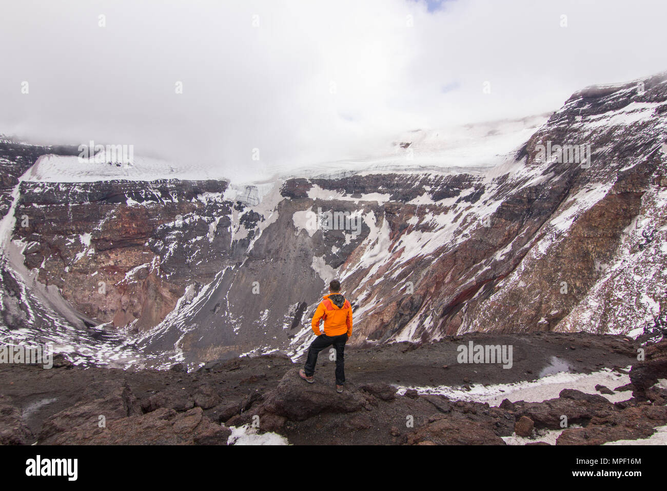 man standing on Tolbachik volcano crater with snow on hills Stock Photo ...