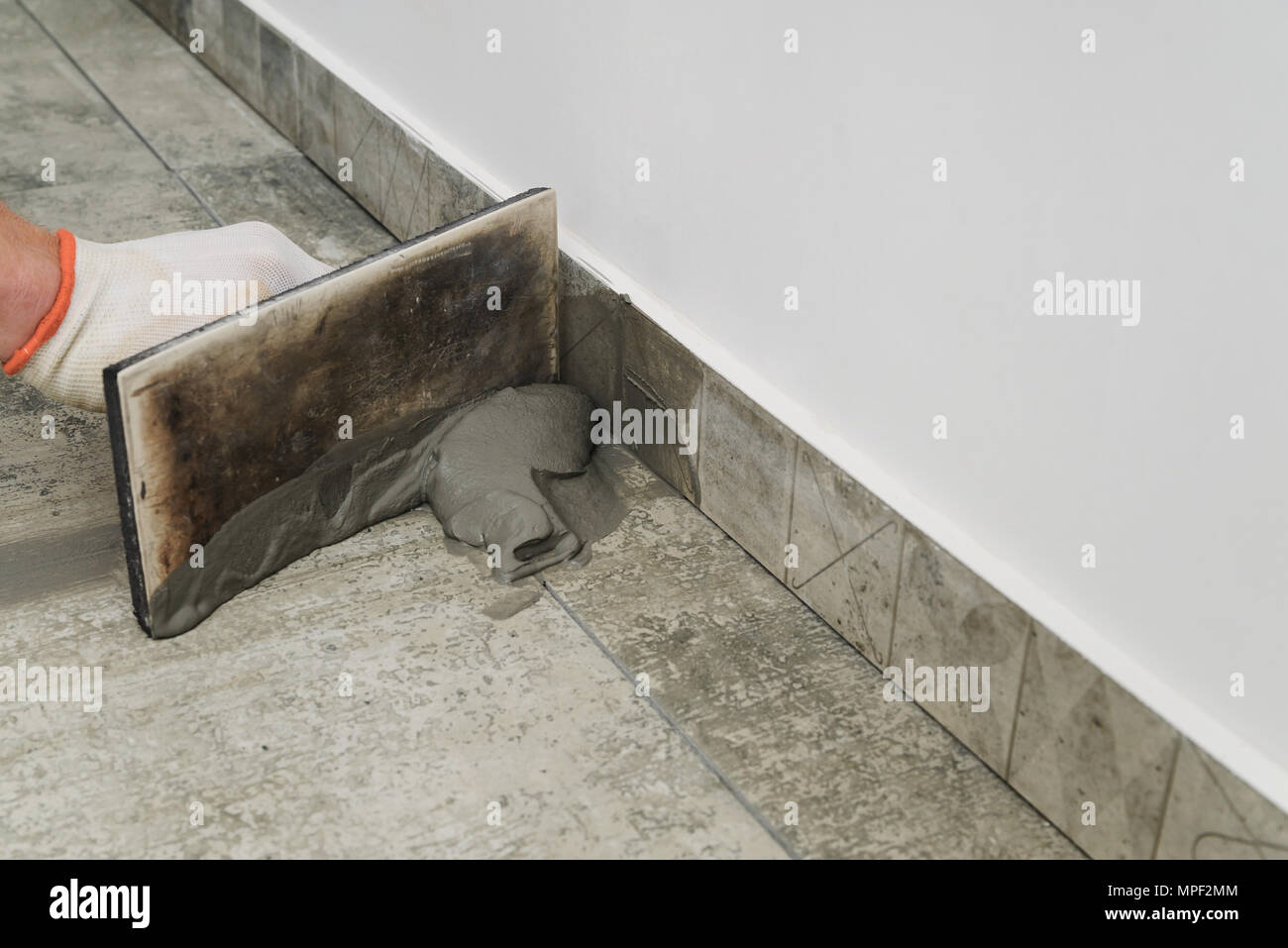 Grouting ceramic tiles. Tilers filling the space between tiles using a ...