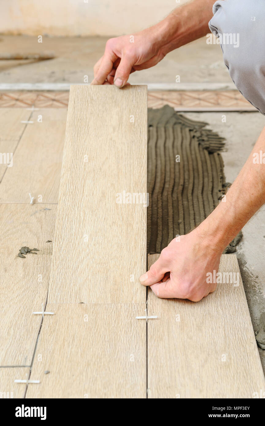 Worker putting tiles on the floor. He places the tile on adhesive Stock ...